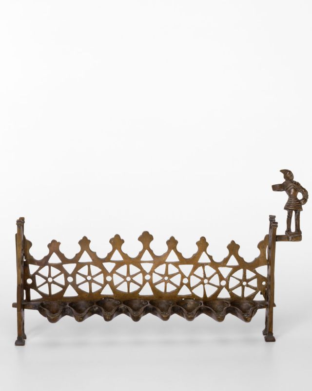 Hanukkah lamp adorned with spoked wheels and servant light shaped like ...